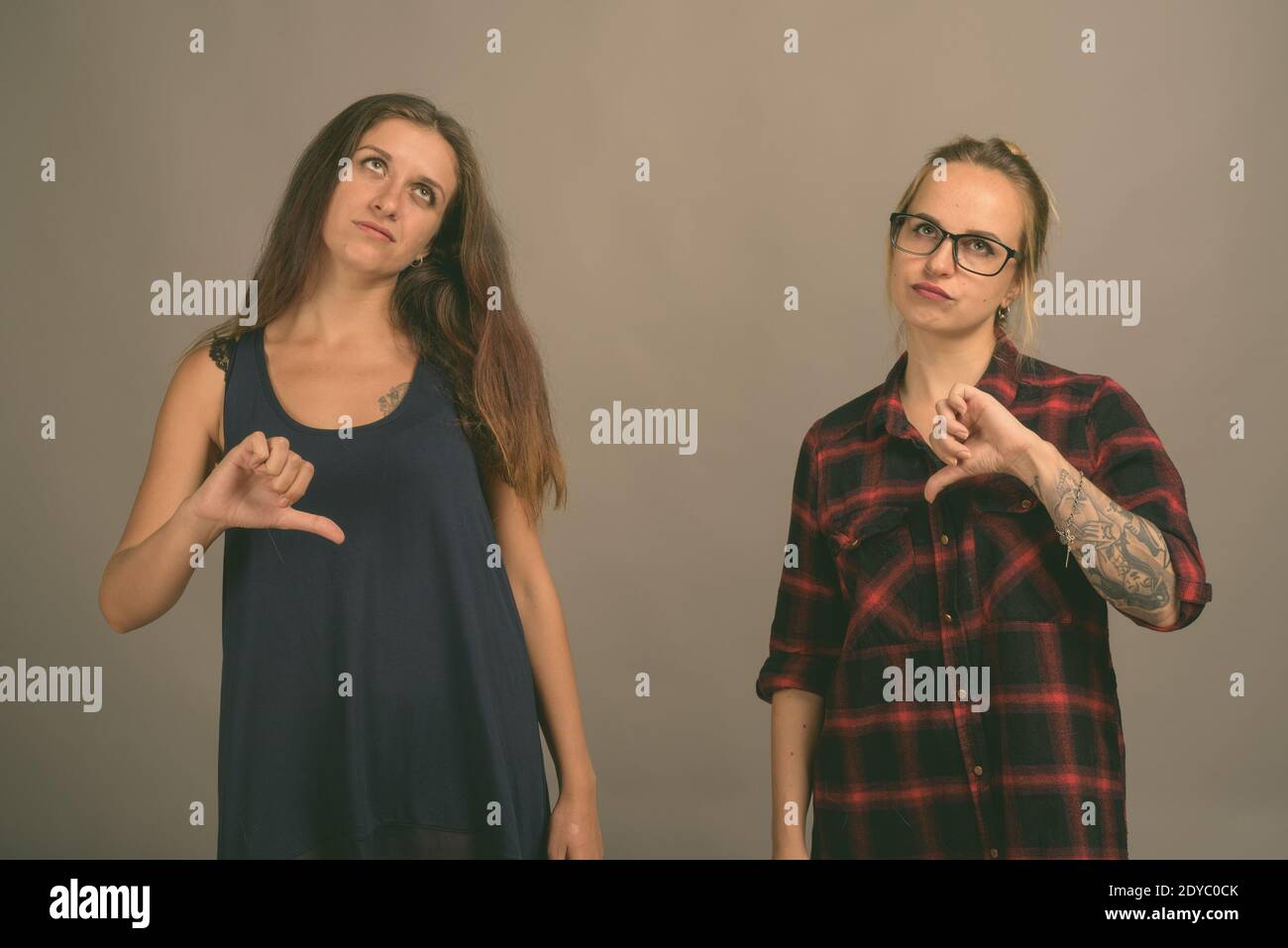 Two young beautiful woman friends against gray background Stock Photo ...