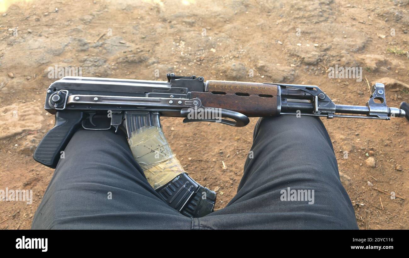 An assault rifle on male knees Stock Photo - Alamy