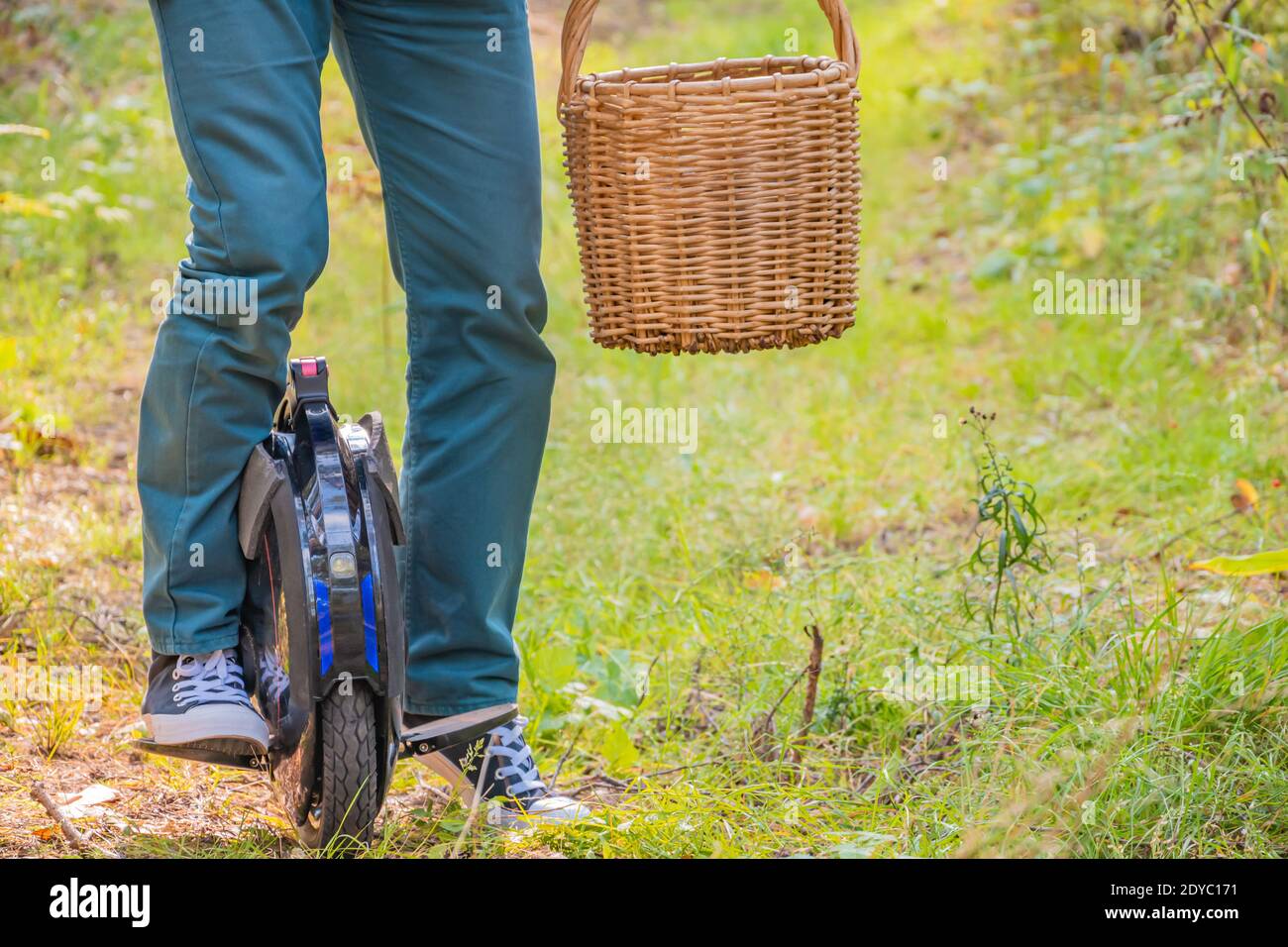 Front view of men's legs on an electric unicycle in the forest. A man ...