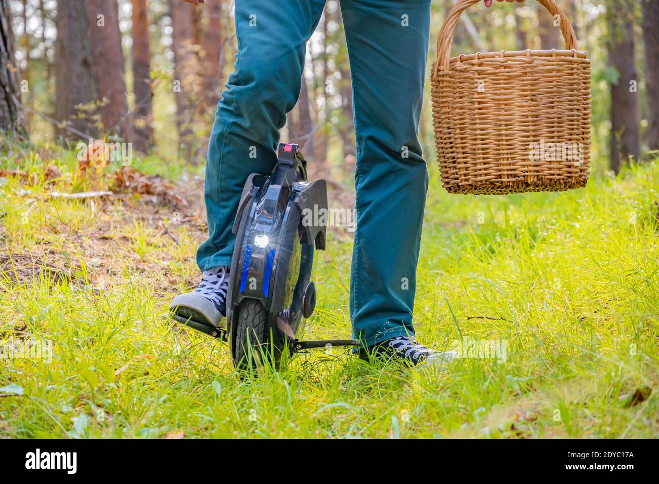 Front view of men's legs on an electric unicycle in the forest. A man ...