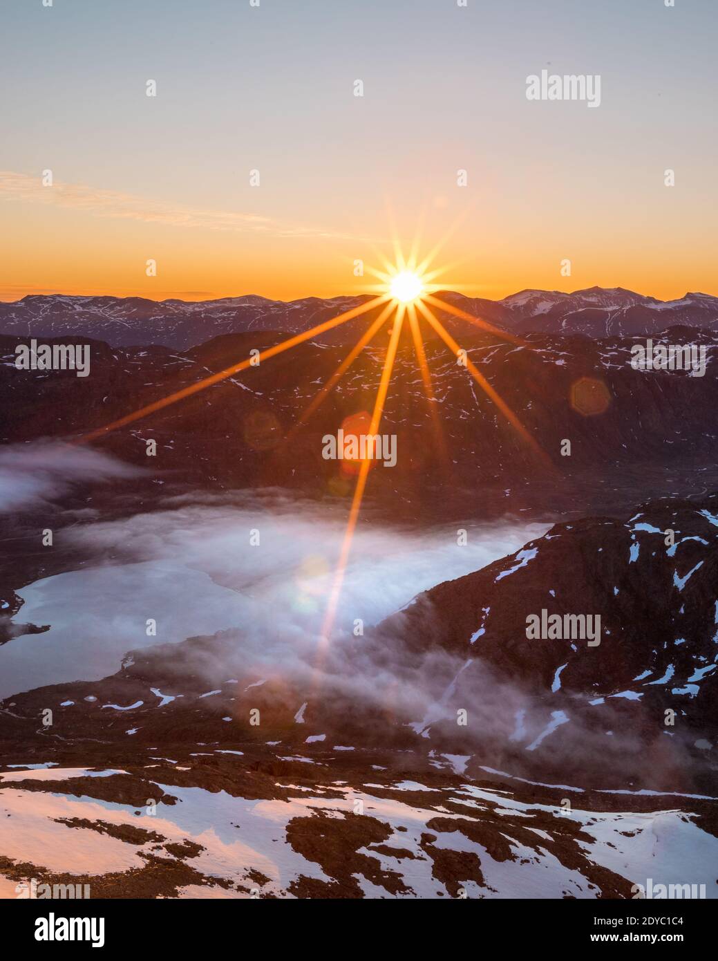 A vertical shot of the snowy mountains peaks above the clouds during the sunrise Stock Photo - Alamy