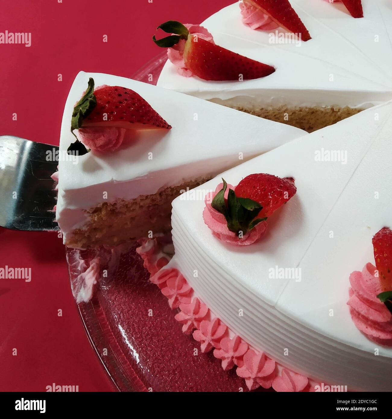 A top view of a cake with strawberry topping, cut in a slic isolated on ...