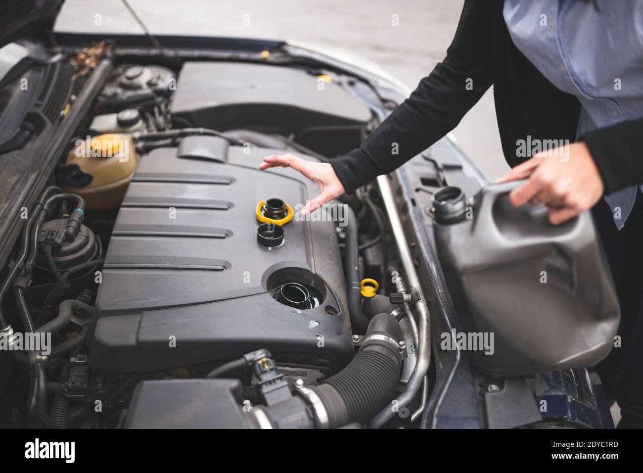 Young Caucasian woman checking the car's engine oil. Car maintenance ...