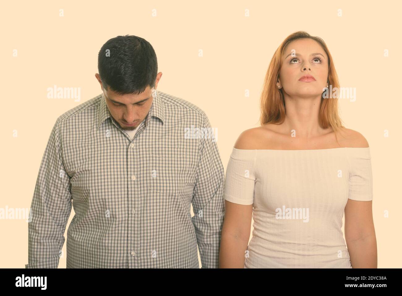 Studio shot of young couple with man looking down and woman looking up ...