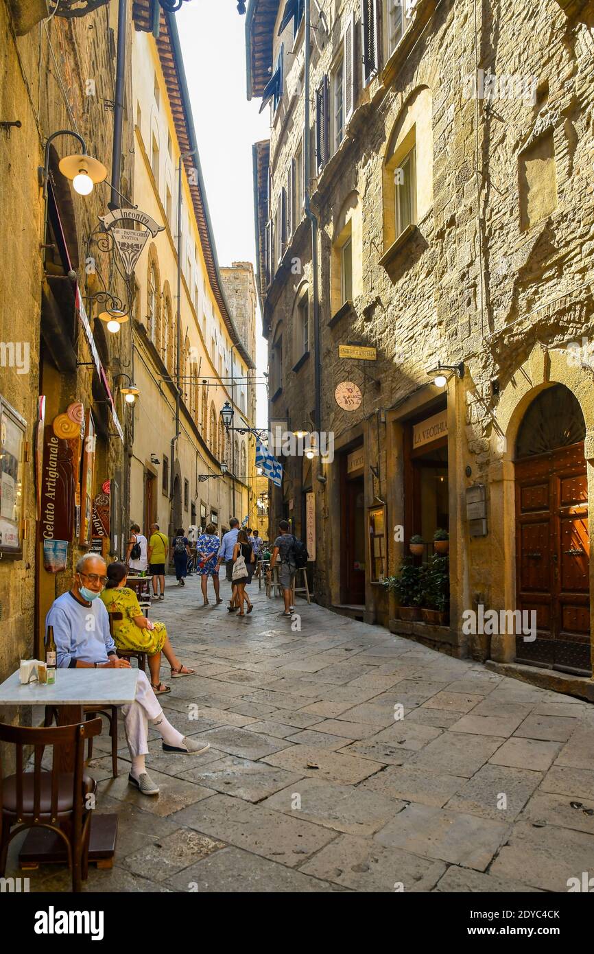 Glimpse of a narrow alley in the old town with people and tourists ...