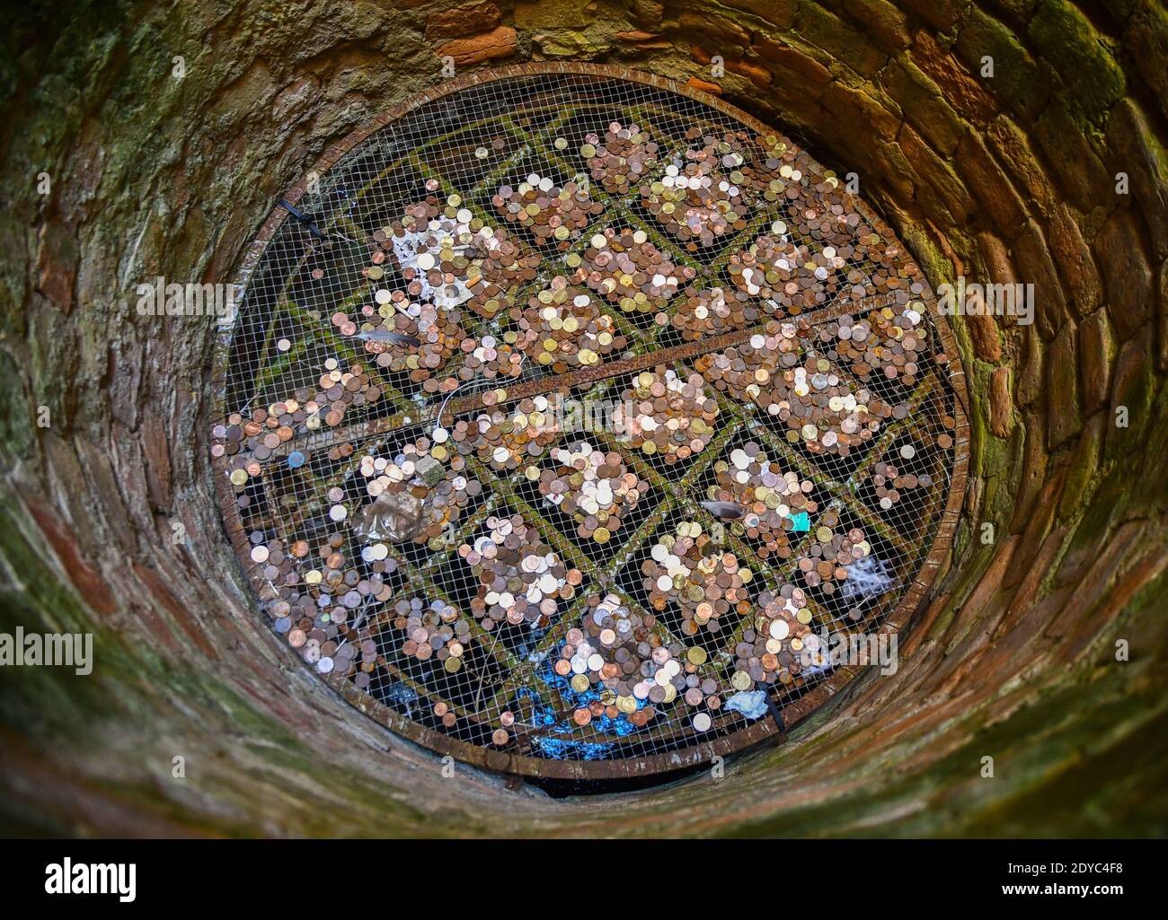 View directly from above a wishing well with many coins on the bottom ...
