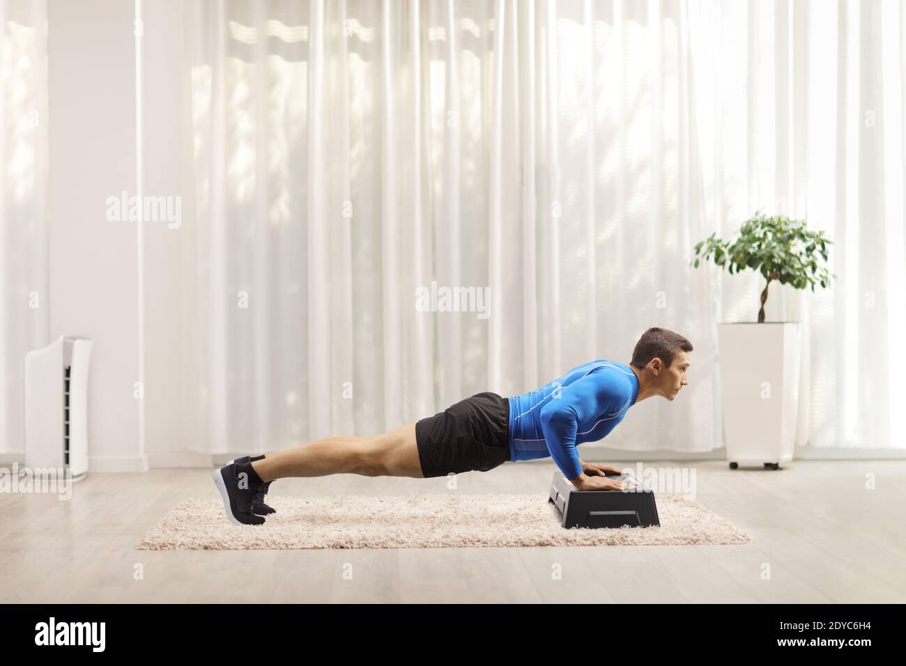 Muscular man doing plank exercise on a step aerobic inside a room Stock ...