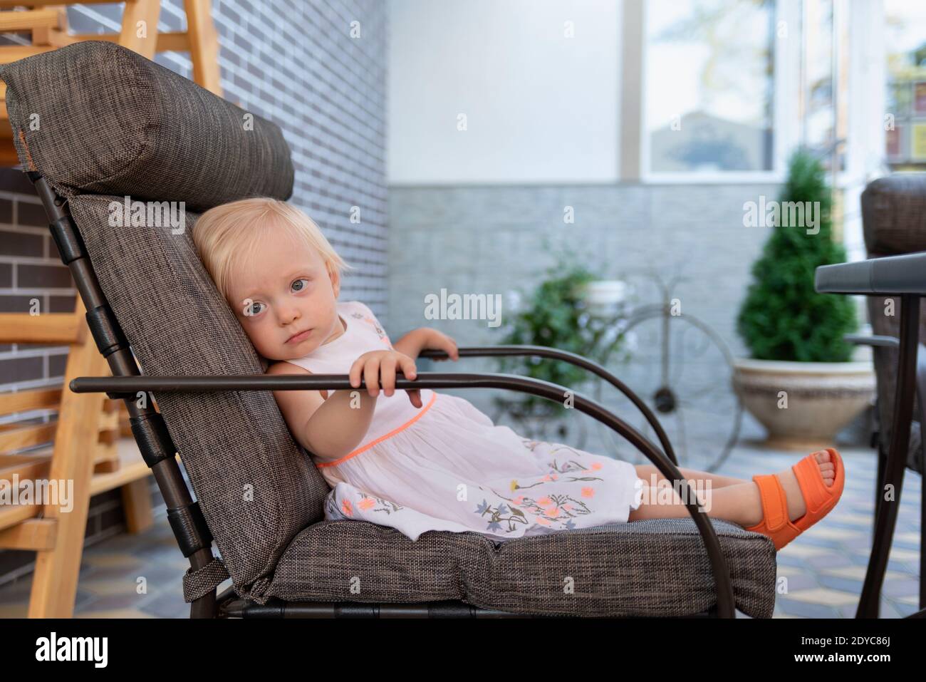 little girl is resting in a large chair. Child is sitting in chair in ...