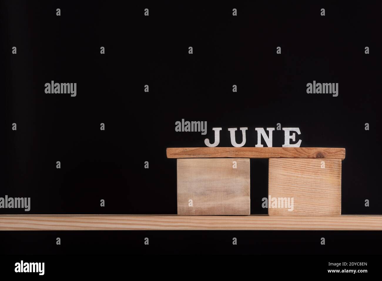 Word June by wooden letters. Black background. Month name. Copy space ...