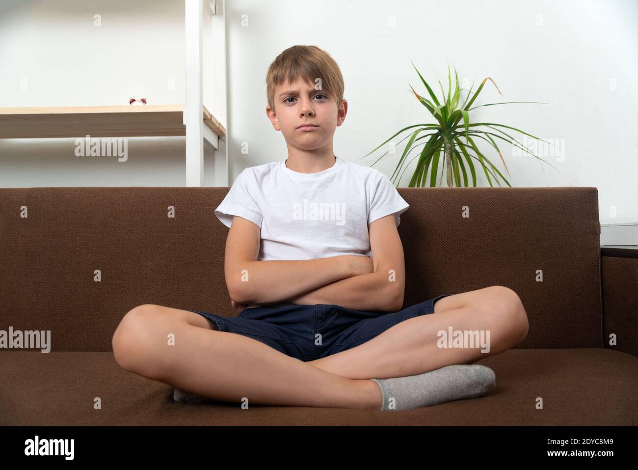 Serious teen boy sitting at home on sofa, legs and arms crossed Stock ...