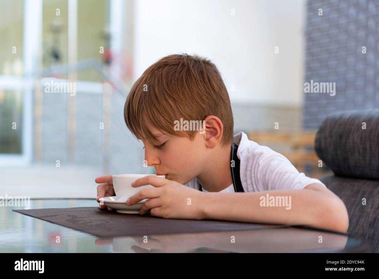 Boy is drinking tea in cafe. Child drinks coffee from white mug Stock ...