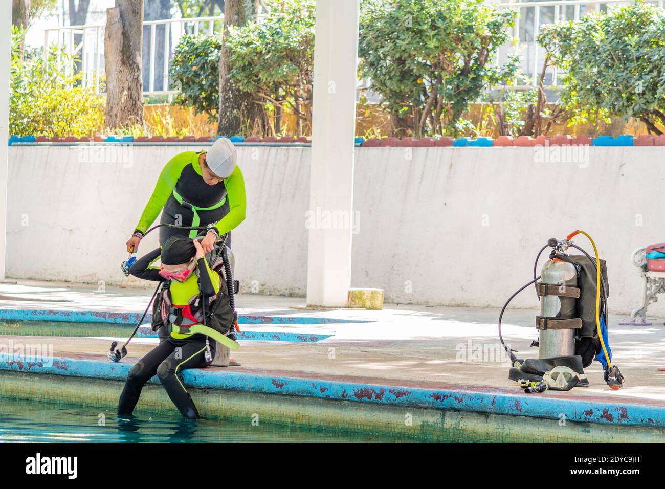 Diving class teacher correctly putting the equipment on her young ...