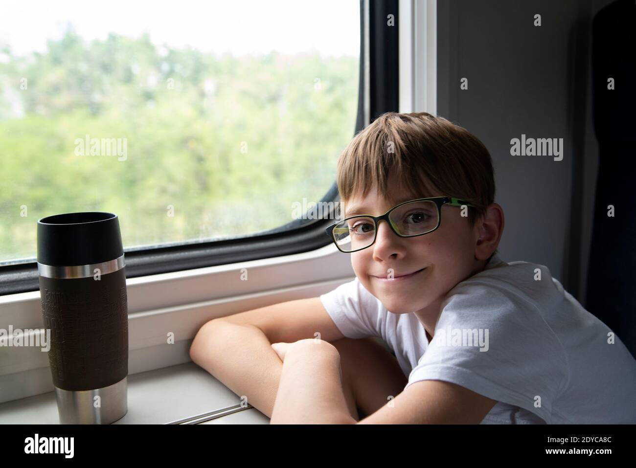 Schoolboy rides on the train. Boy with glasses sits at table on train ...