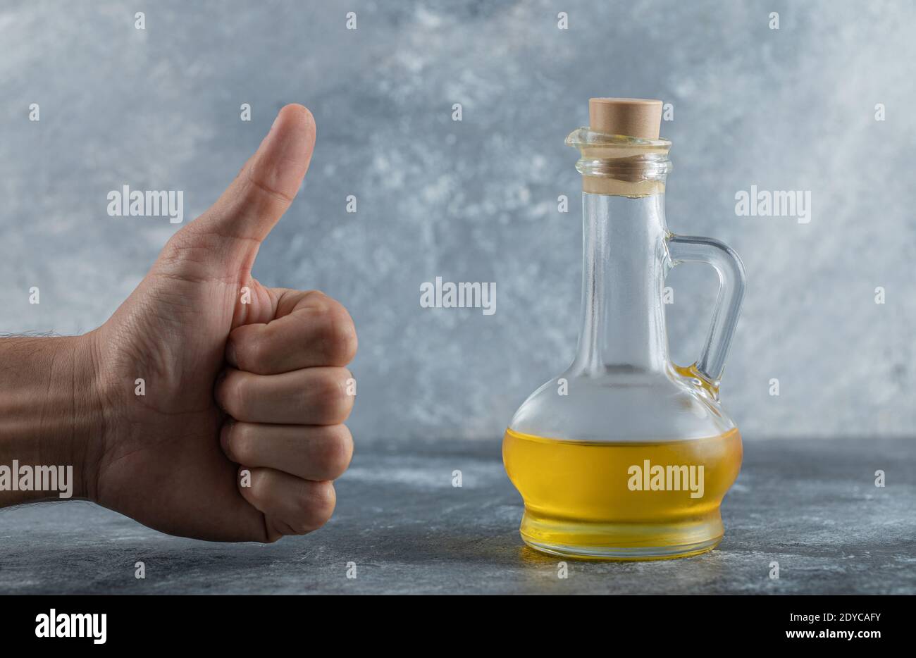 Man gesturing thumb up to bottle of oil Stock Photo - Alamy