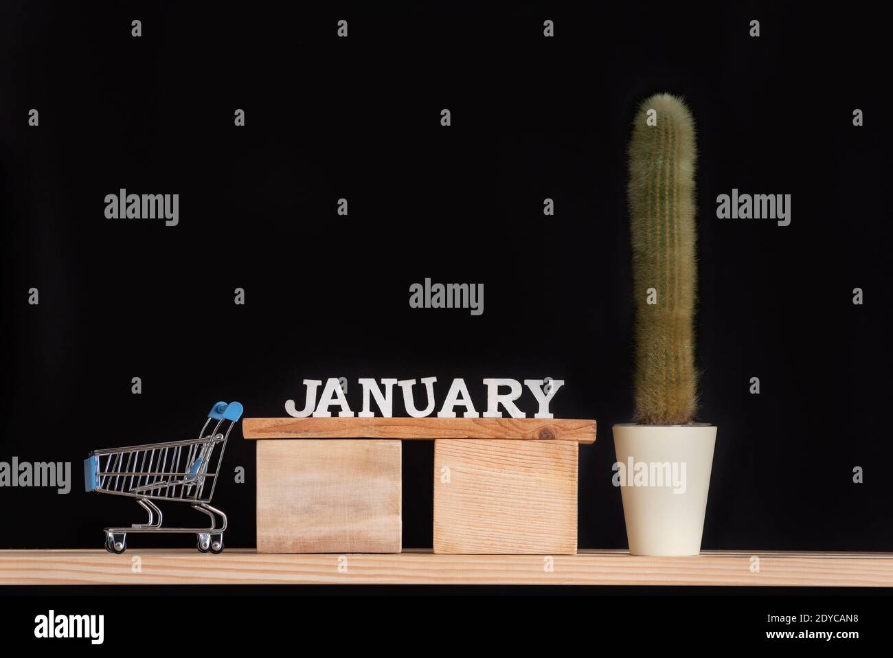 Wooden calendar of January cactus and miniature trolley card on black ...
