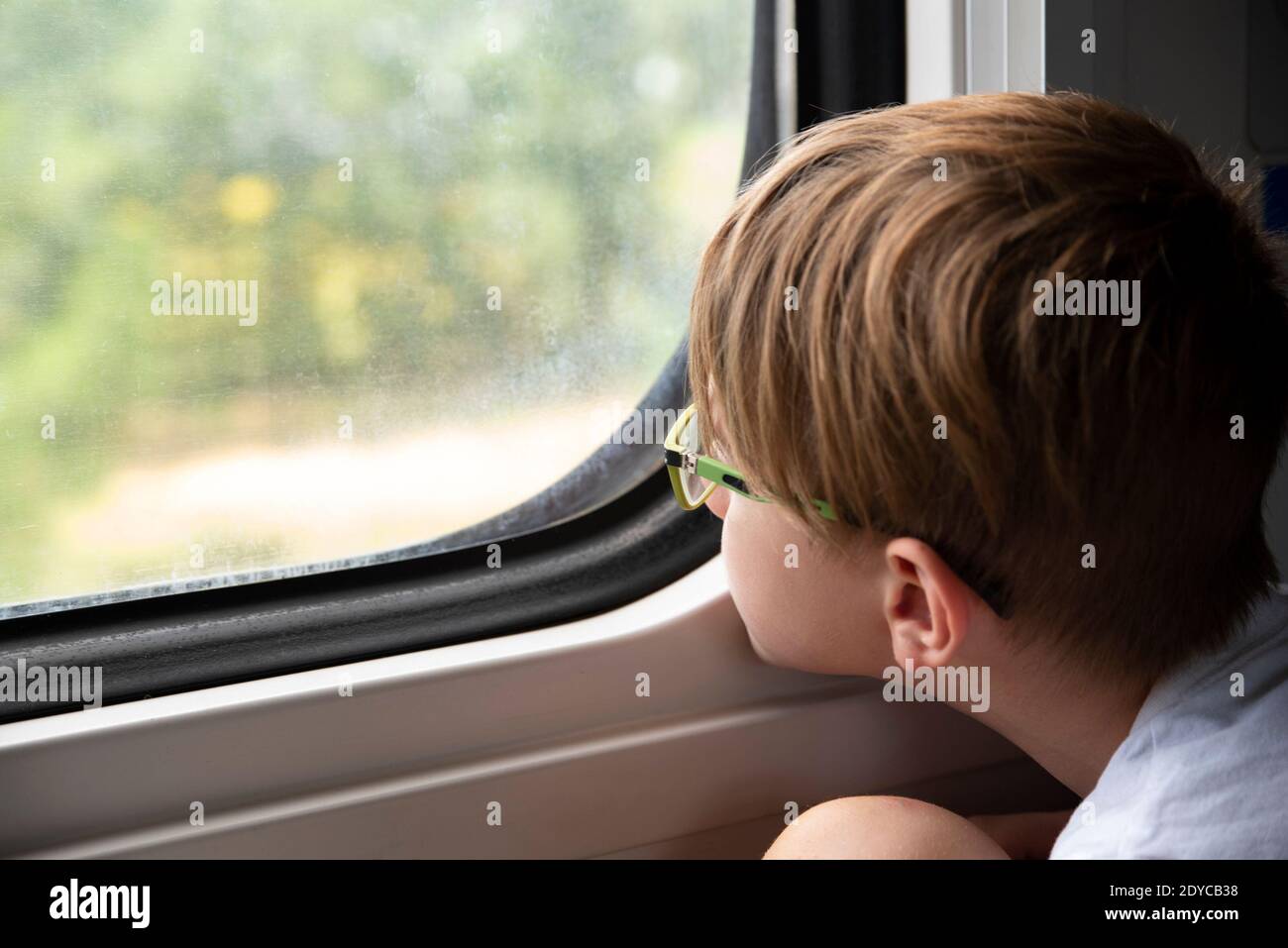 boy looks thoughtfully out the train window. Traveling by train with ...