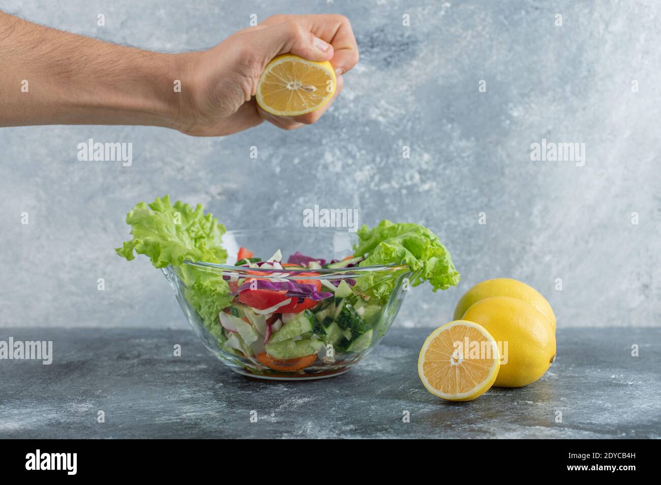 Man squeezing lemon to plate of mixed vegetable salad Stock Photo - Alamy