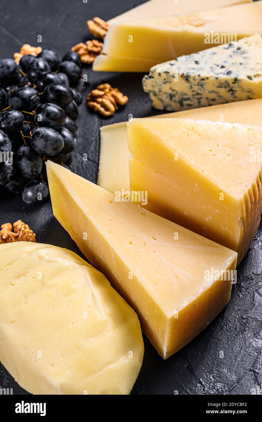 Different types of delicious cheese with walnuts and grapes. Black ...