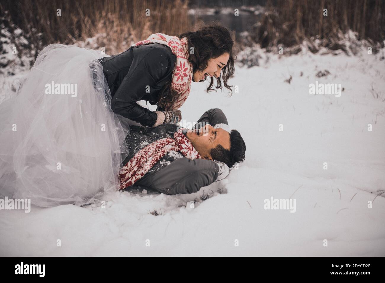 wedding couple running lying in snow laughing having fun playing ...