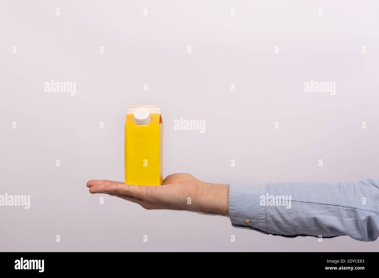 Blank yellow cardboard bag with cap on mens palm. Packet of juice or ...