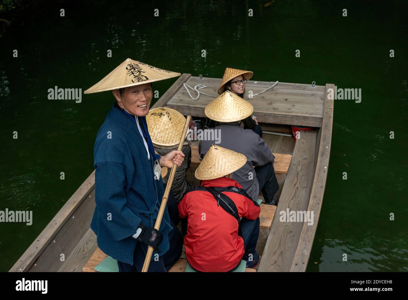 Boatman poling visitors in a wooden boat around the lakes, Ritsurin ...