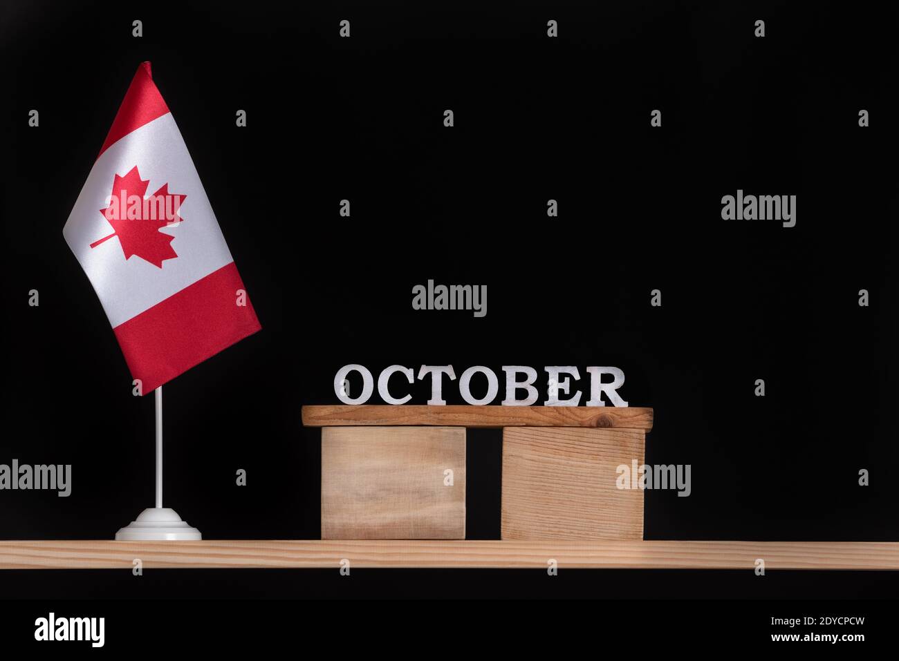 Wooden calendar of October with Canadian flag on black background ...