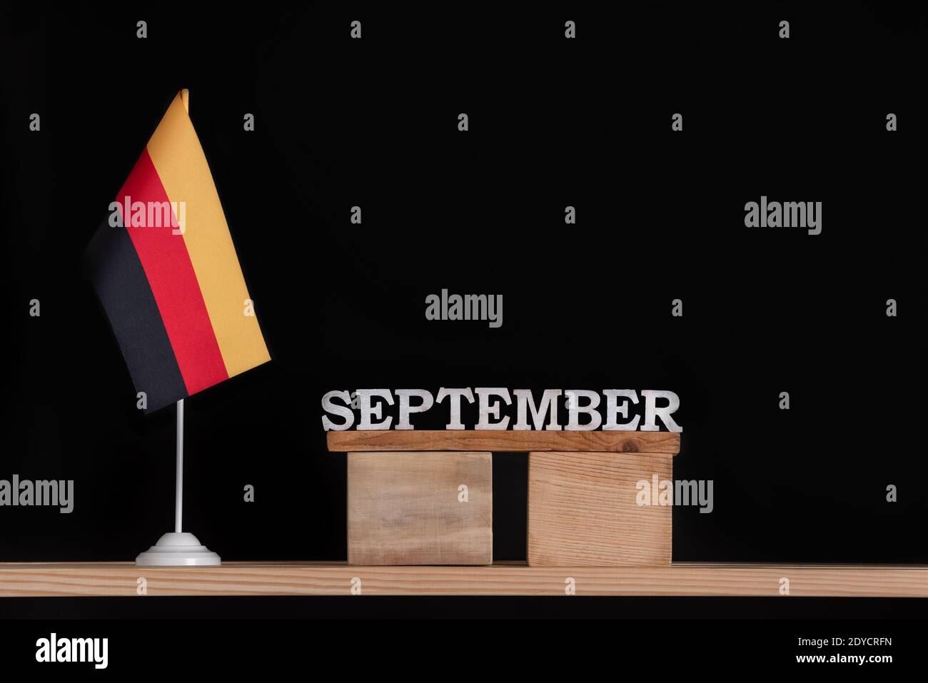 Wooden calendar of September with German flag on black background ...