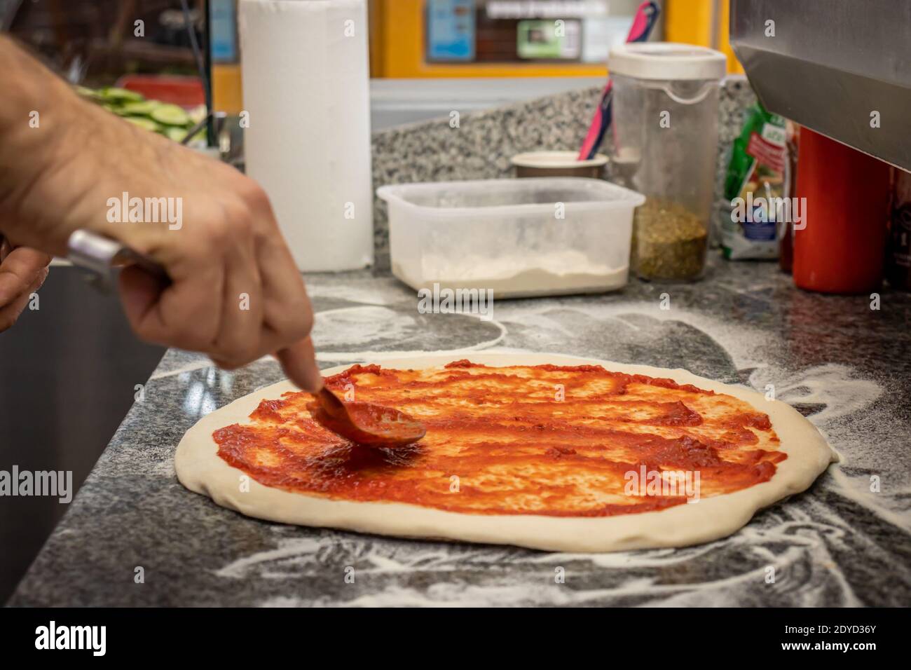 A man making a margherita pizza in a local pizza and gyros restaurant ...