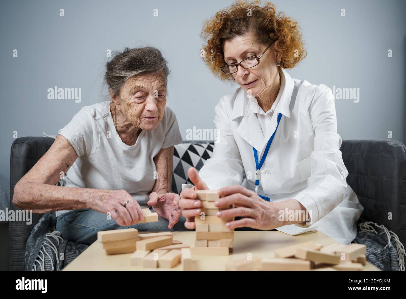 Senior woman playing Jenga, build tower of blocks. Elderly doctor in ...
