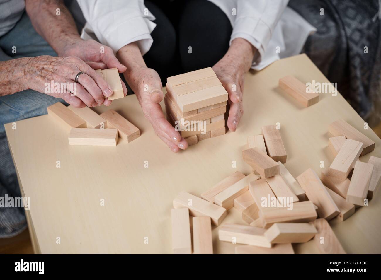 Senior woman practice skills, build wooden blocks, build tower and try ...