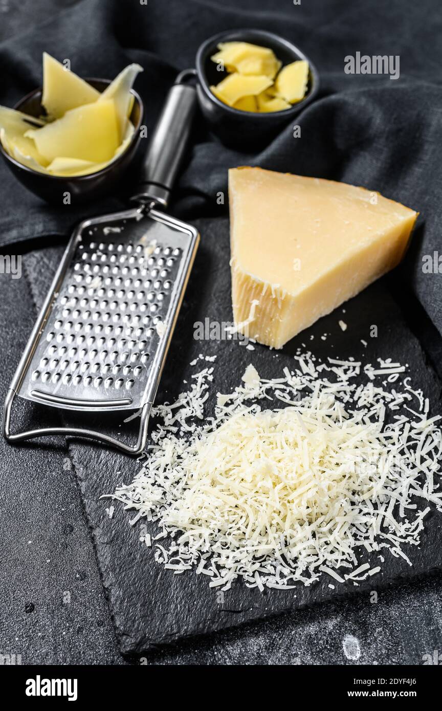 Italian hard Parmesan cheese slice, cut, grated. Black background. Top ...