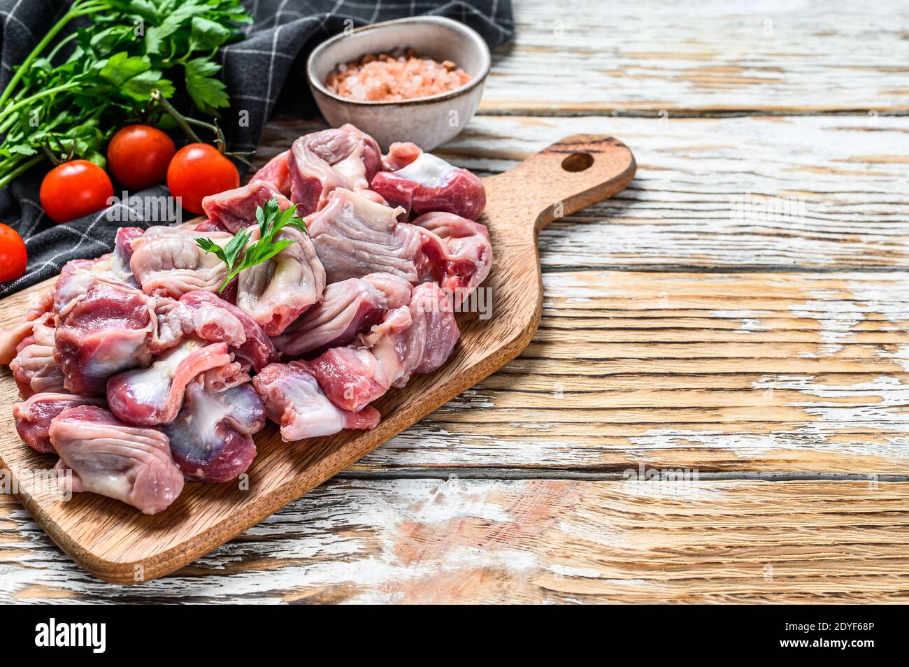 Raw uncooked Bird chicken giblets gizzards, stomachs on a cutting board ...