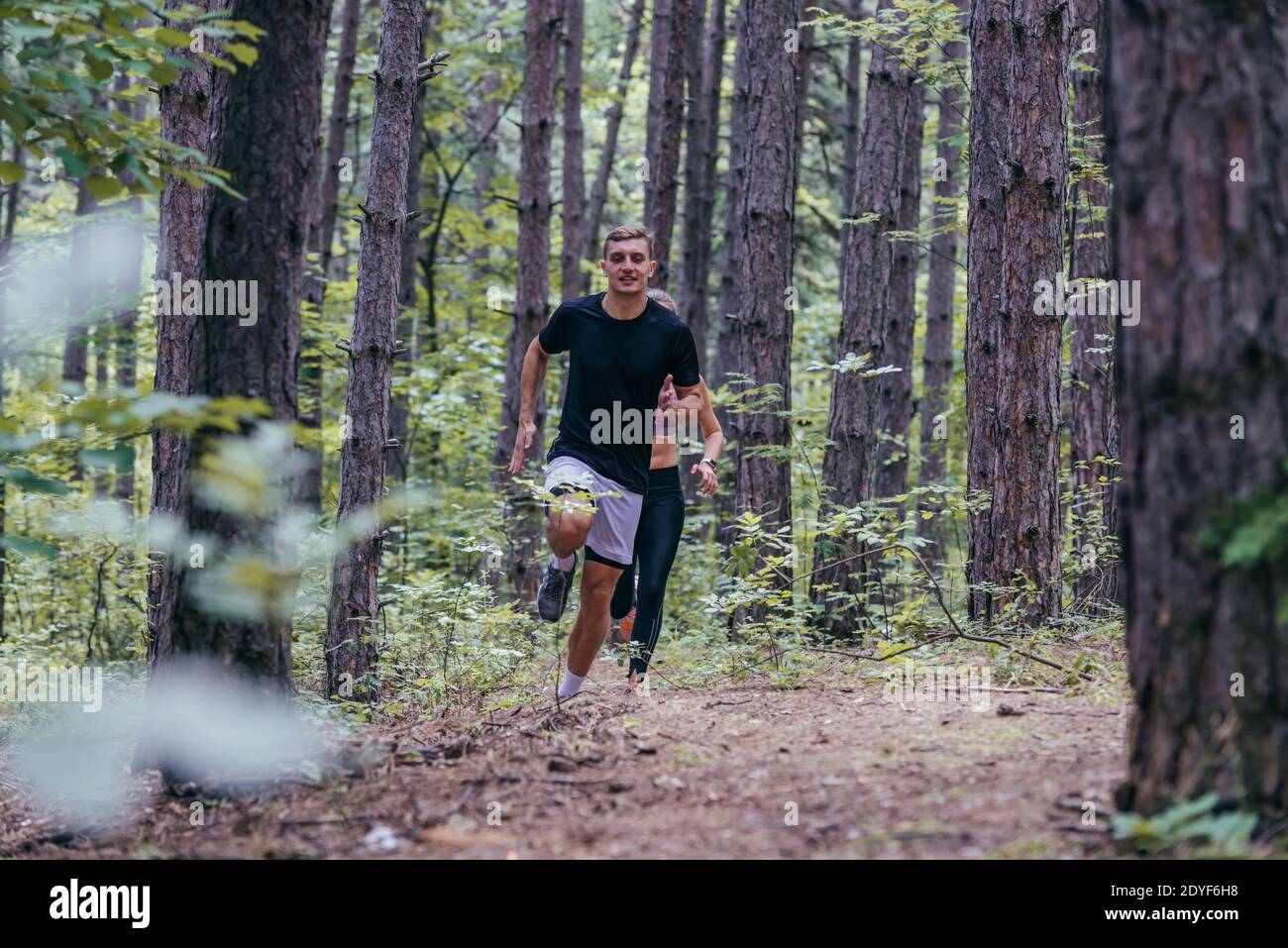 Strong male runner jogging for marathon on forest road Stock Photo - Alamy