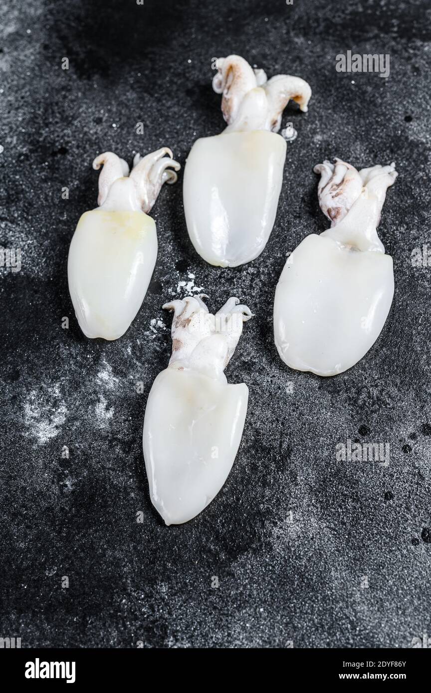 Raw mini cuttlefish on the table. Black background. Top view Stock ...
