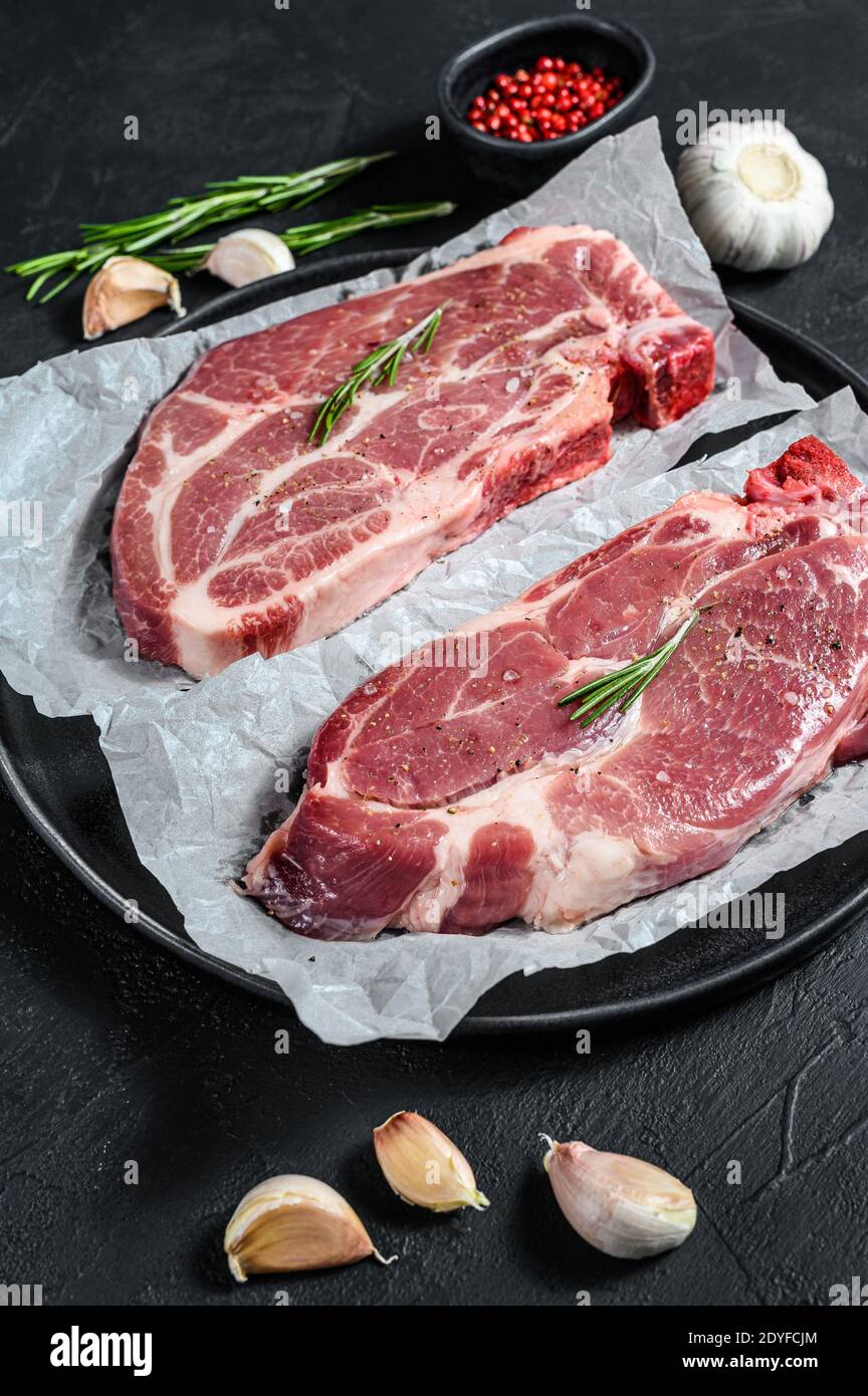 Raw pork steak. Marble meat on parchment paper. Black background. Top ...