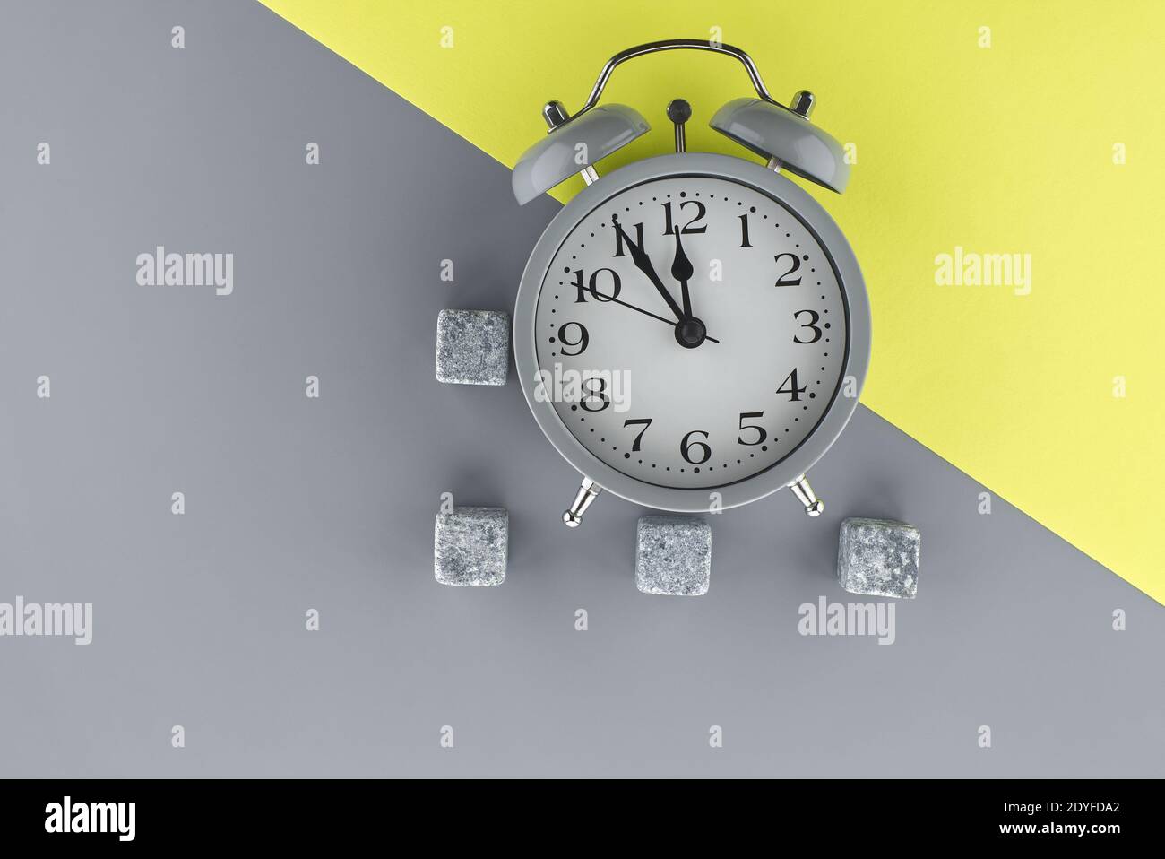 Alarm clock on a two tone grey and yellow background with copy space ...