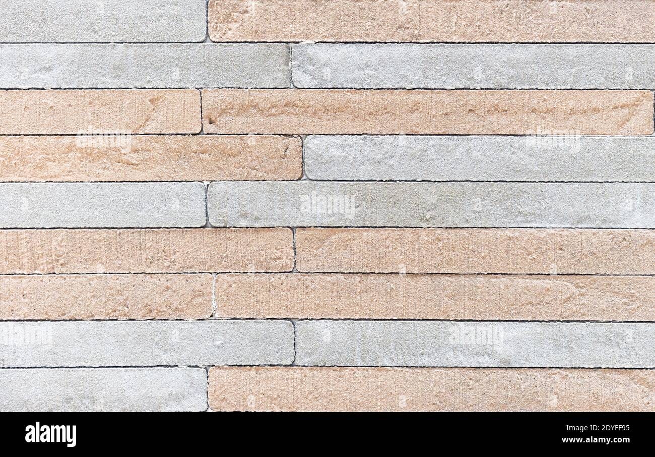 Texture of a rough stone wall made of gray and beige rectangular blocks ...
