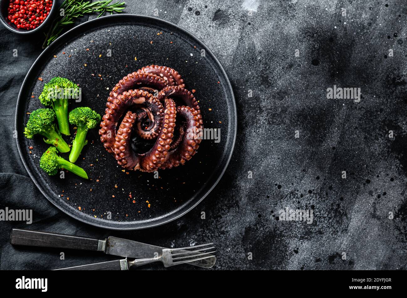 Grilled whole octopus with broccoli on a plate. Black background. Top ...