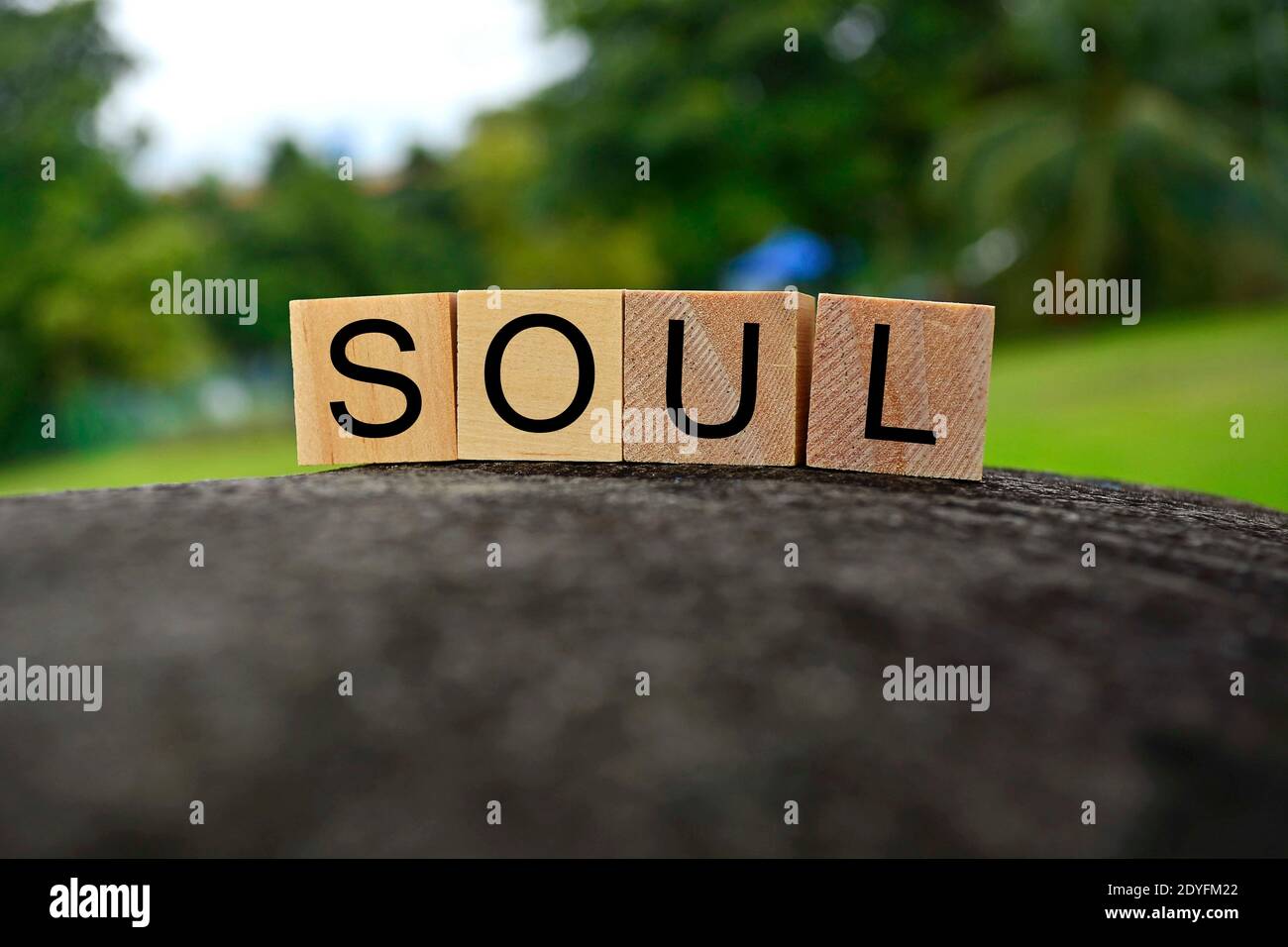 Soul text on wooden cube block on top of big stone with blurred sky ...