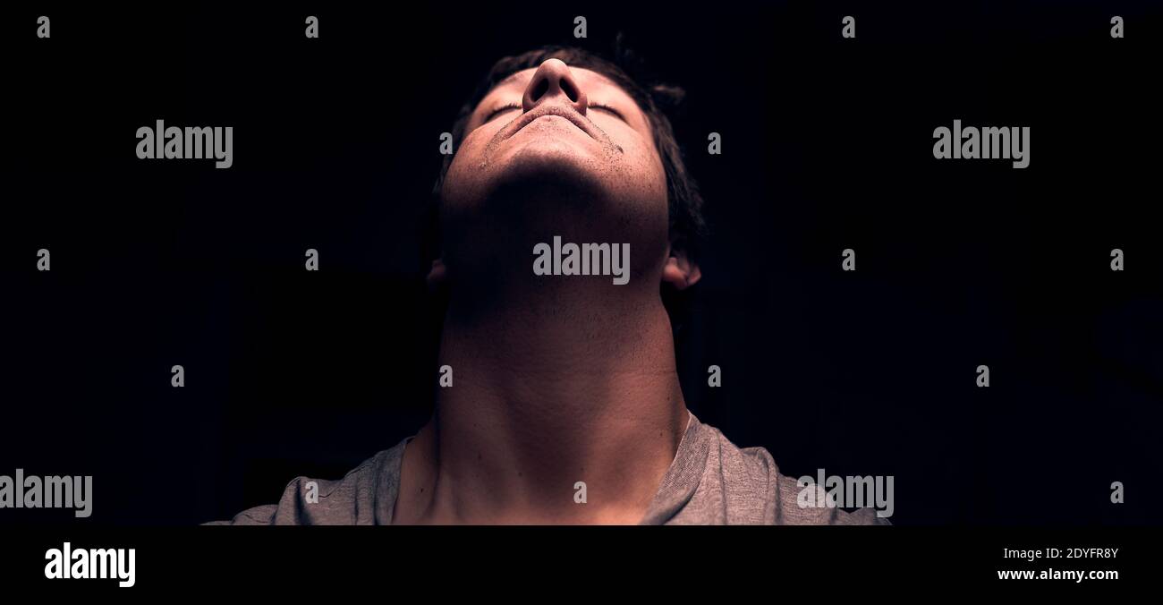 man with strong neck looking up boundless with black background. see ...