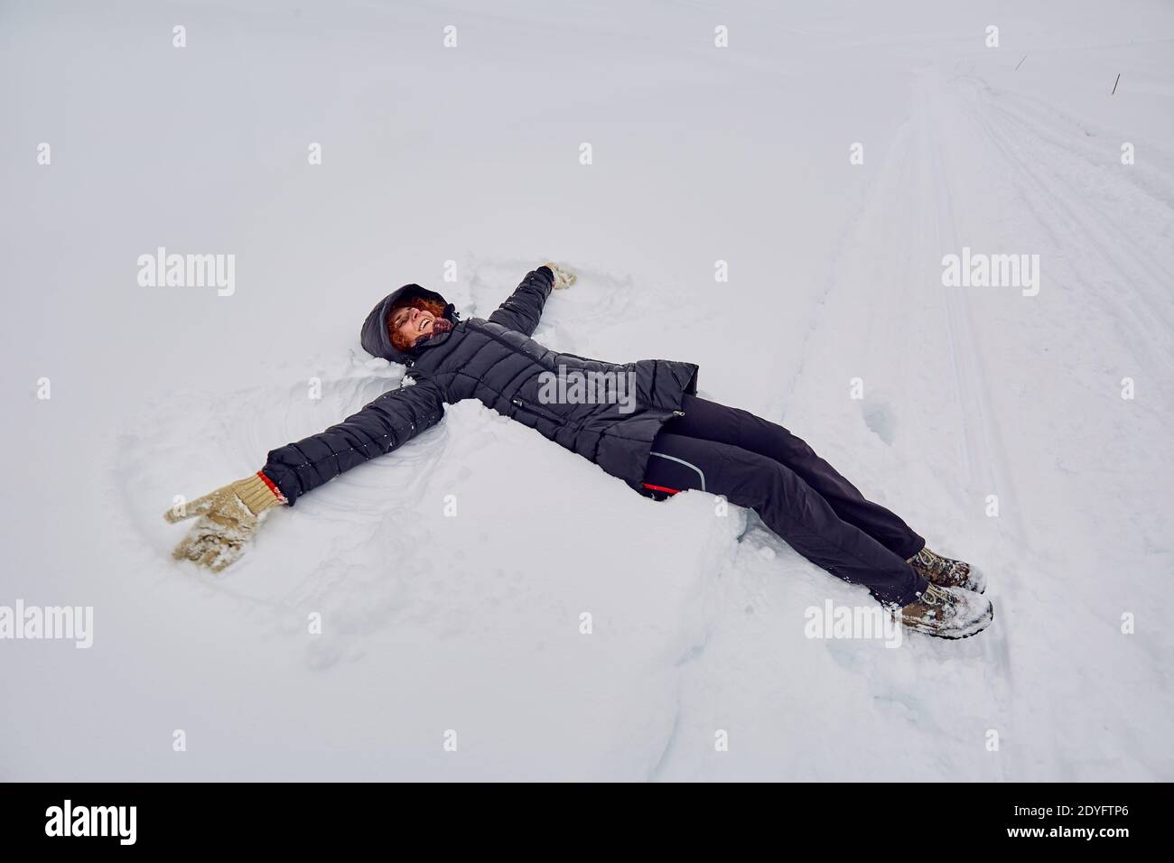 Woman making snow angels lying on her back Stock Photo - Alamy