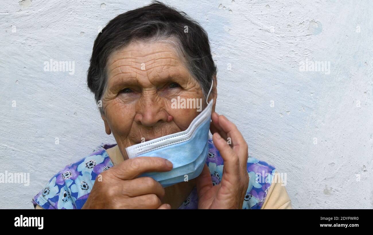 Elderly woman take off medical single-use mask with both hands ...