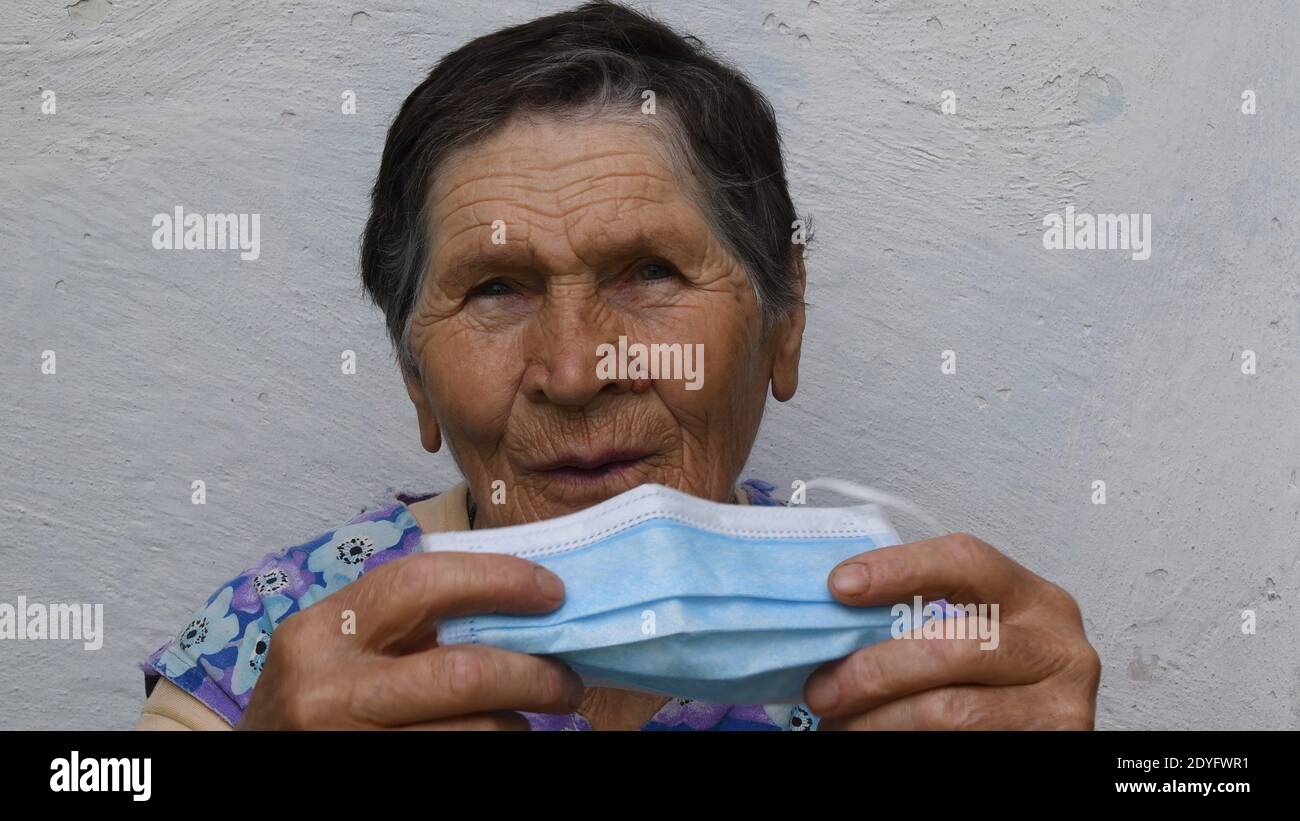 Elderly woman holds medical mask in hands. Portrait of wrinkled female ...