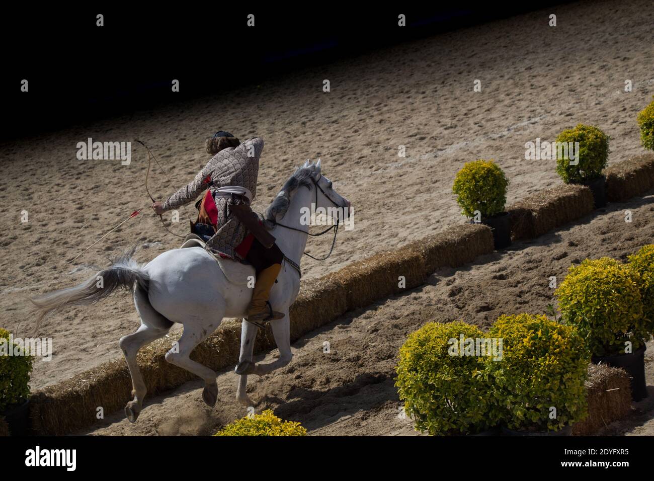 A horseman with folk costumes, shooting an arrow while riding on ahorse ...