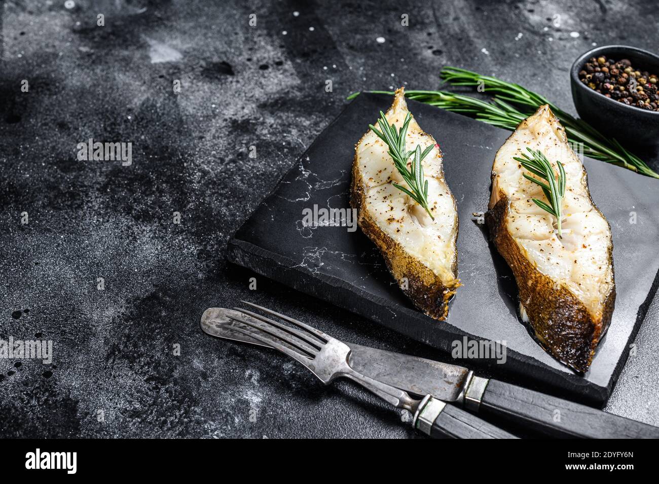 Halibut fish steak with rosemary. Black background. Top view. Copy ...