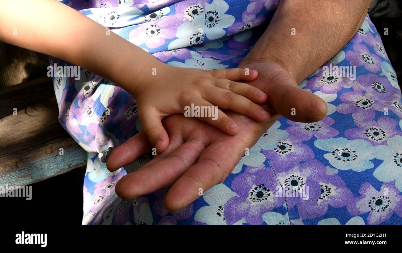 Small kid hand atop opened hand palm of old lady. Great grandmother ...