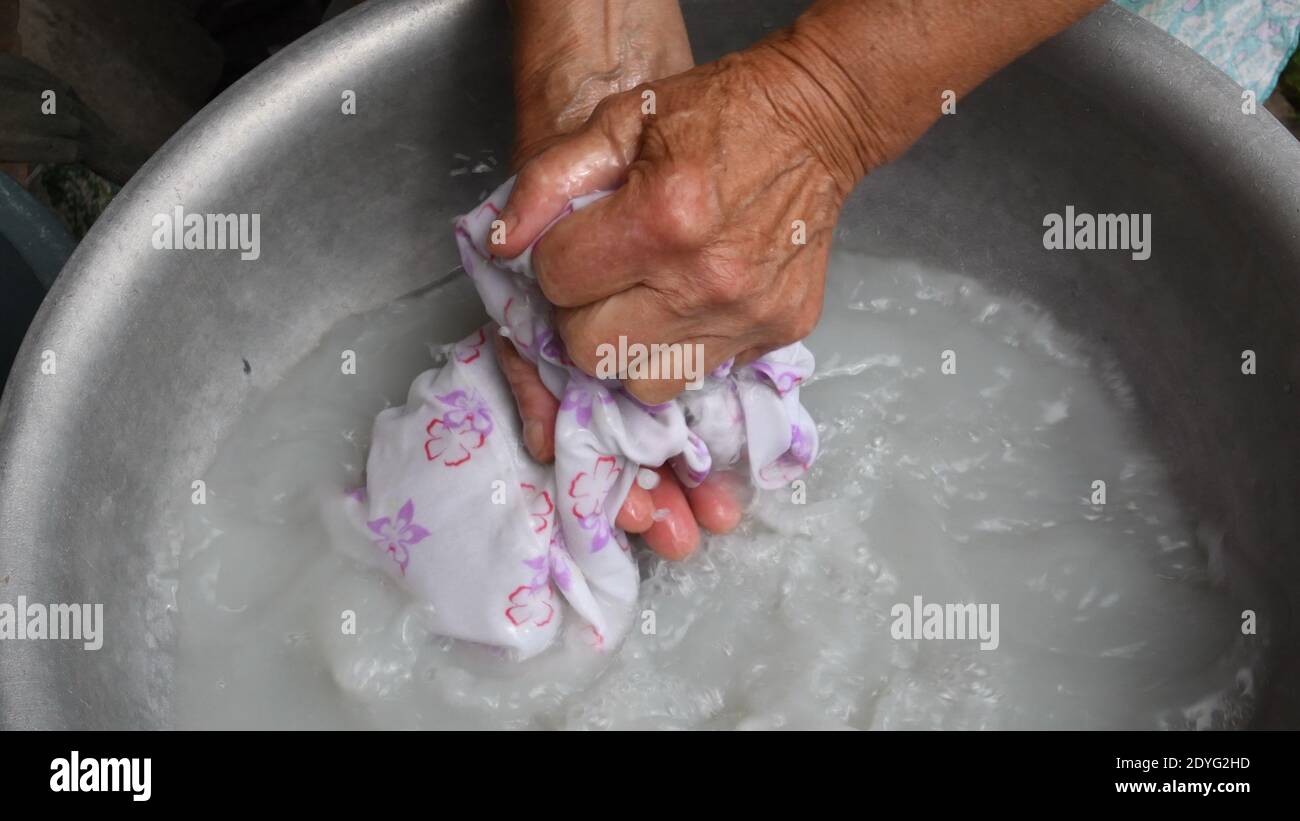 Elderly female hands washing clothes in old metal basin. Obsolete way ...