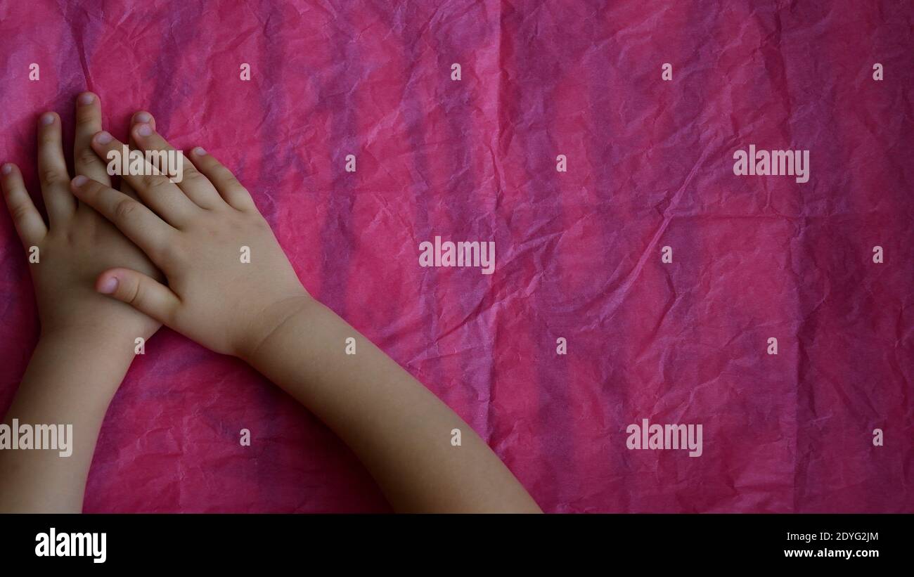 Toddler hands ccrossed on crumpled tissue paper with copy space ...