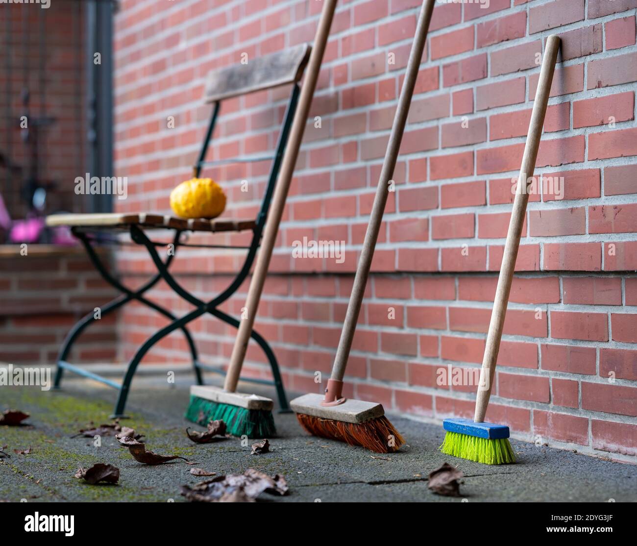 Two normal brooms and a small broom for kids are leaning against the ...