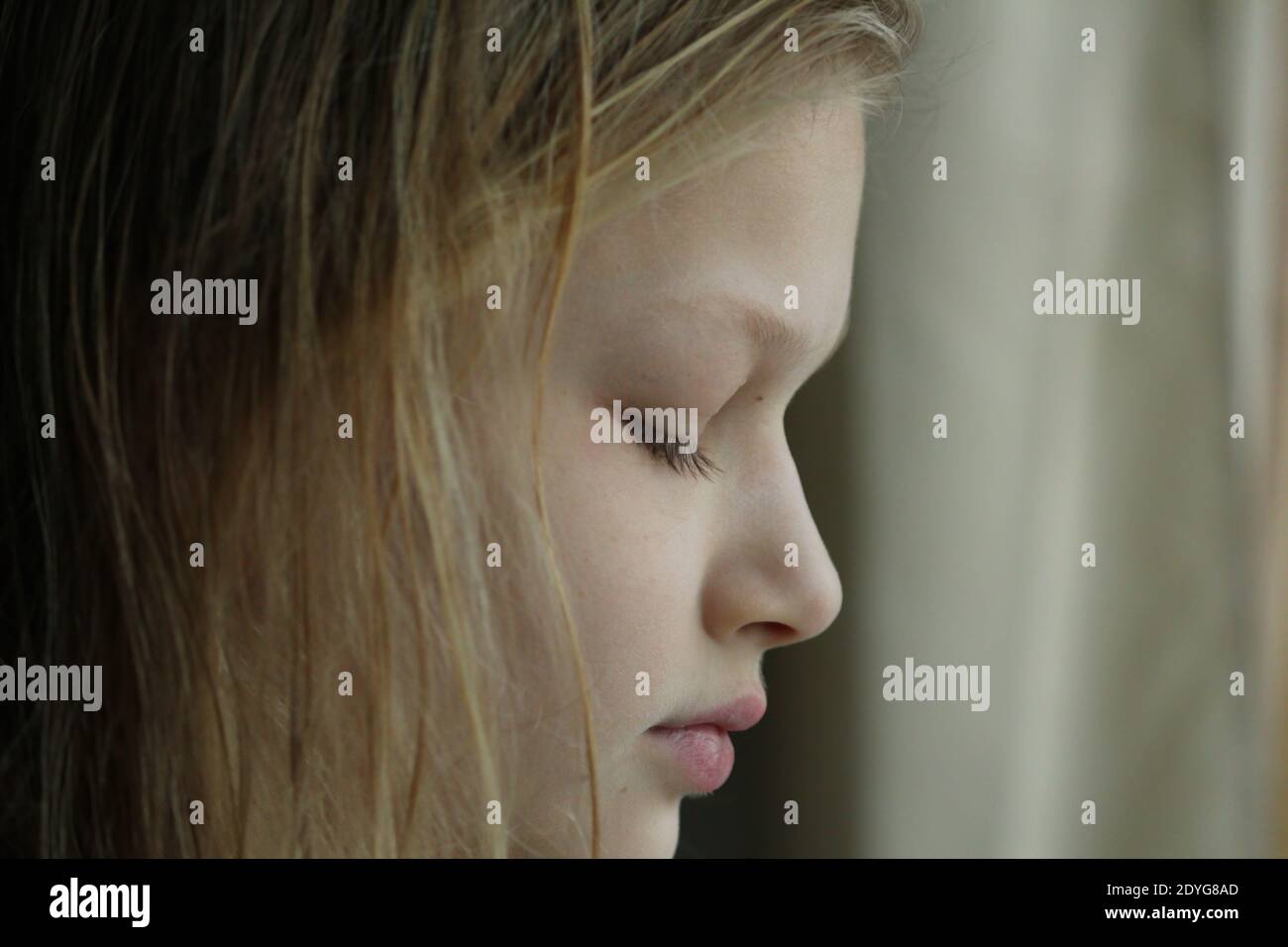 The face of a beautiful pensive teenage girl with loose blond hair and ...